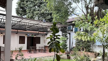 Um pátio com vasos de plantas, um pavimento de azulejos e um edifício tradicional com telhado em azulejos.