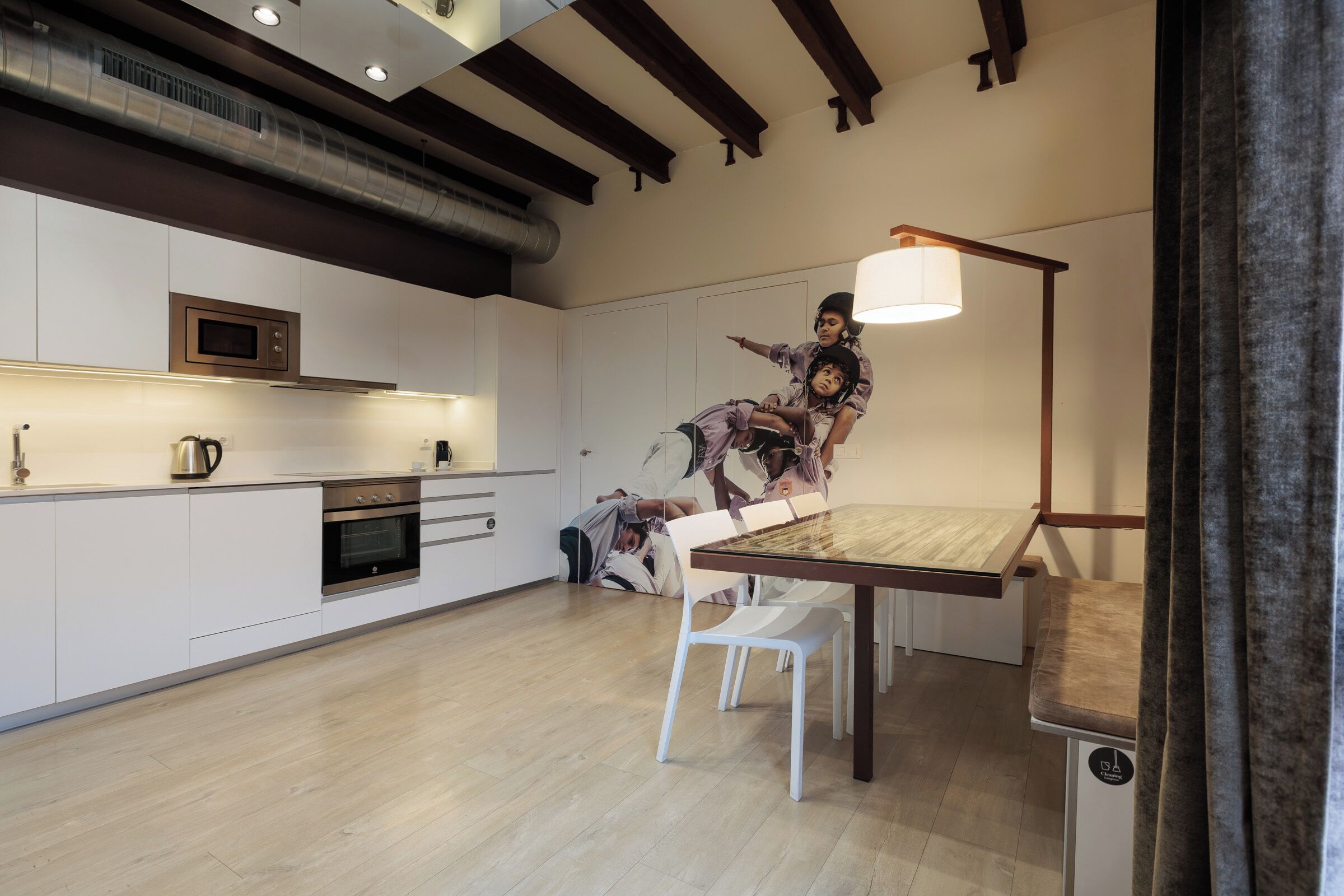 Cozinha moderna com armários brancos, forno de aço inoxidável e mesa de jantar com cadeiras.