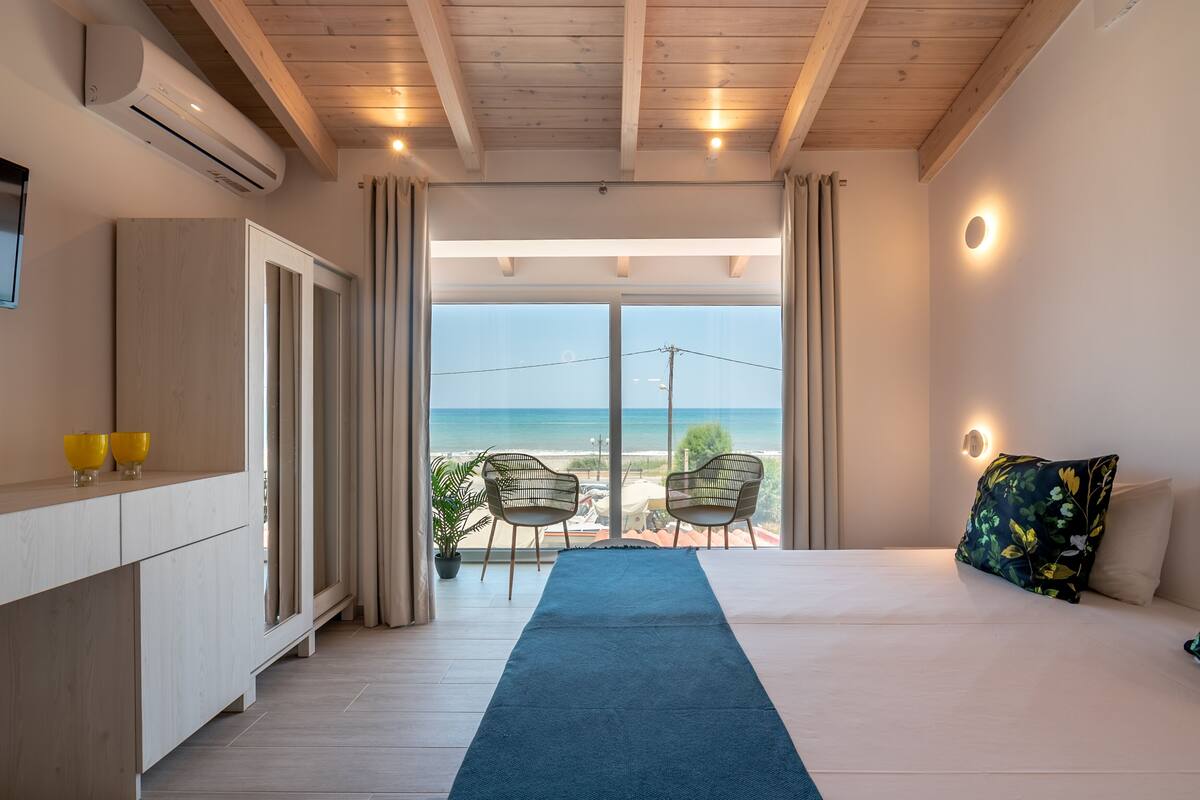 Quarto com cama, escrivaninha e vista para o mar.