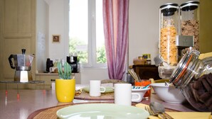 Uma mesa com máquina de café, chávenas e um prato.