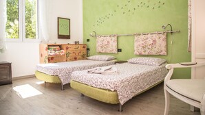 Quarto com duas camas, uma cômoda de madeira, uma cadeira e uma janela com cortinas.