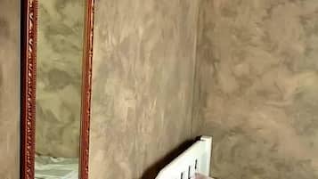 Quarto com cabeceira de madeira, almofada floral e um espelho grande com moldura decorativa.
