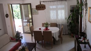 Uma sala de jantar com uma mesa redonda, cadeiras e um lustre.