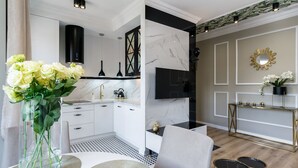 Cozinha moderna com armários brancos, console preto e dourado e backsplash de mármore.