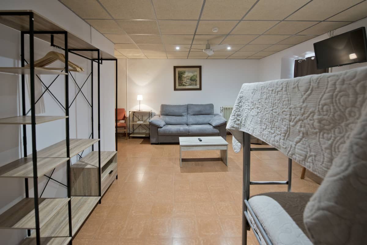 Uma sala de estar moderna com um sofá cinzento, uma mesa de centro de madeira e uma TV fixada na parede.