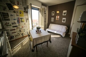 Um espaço de estar compacto com área de jantar, um sofá e uma parede decorada com diversas imagens.