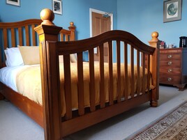 Quarto com cama de madeira, cômoda e porta.