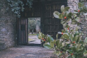 Um edifício de pedra com uma grande porta de madeira e um caminho que leva a um pátio.