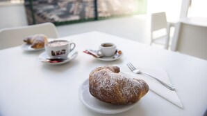 Uma mesa com um croissant, uma xícara de café e um pastelaria sobre um pano de mesa branco.