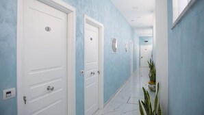 Um corredor com portas brancas, paredes azul-claras e chão de azulejos.