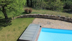 Piscina com parede de pedra e área gramada.