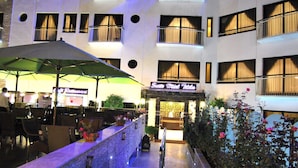 Um saguão de hotel com balcão de recepção, escada e varanda florida.