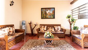 Uma sala de estar com um sofá, uma mesa de centro com um arranjo floral e um quadro na parede.