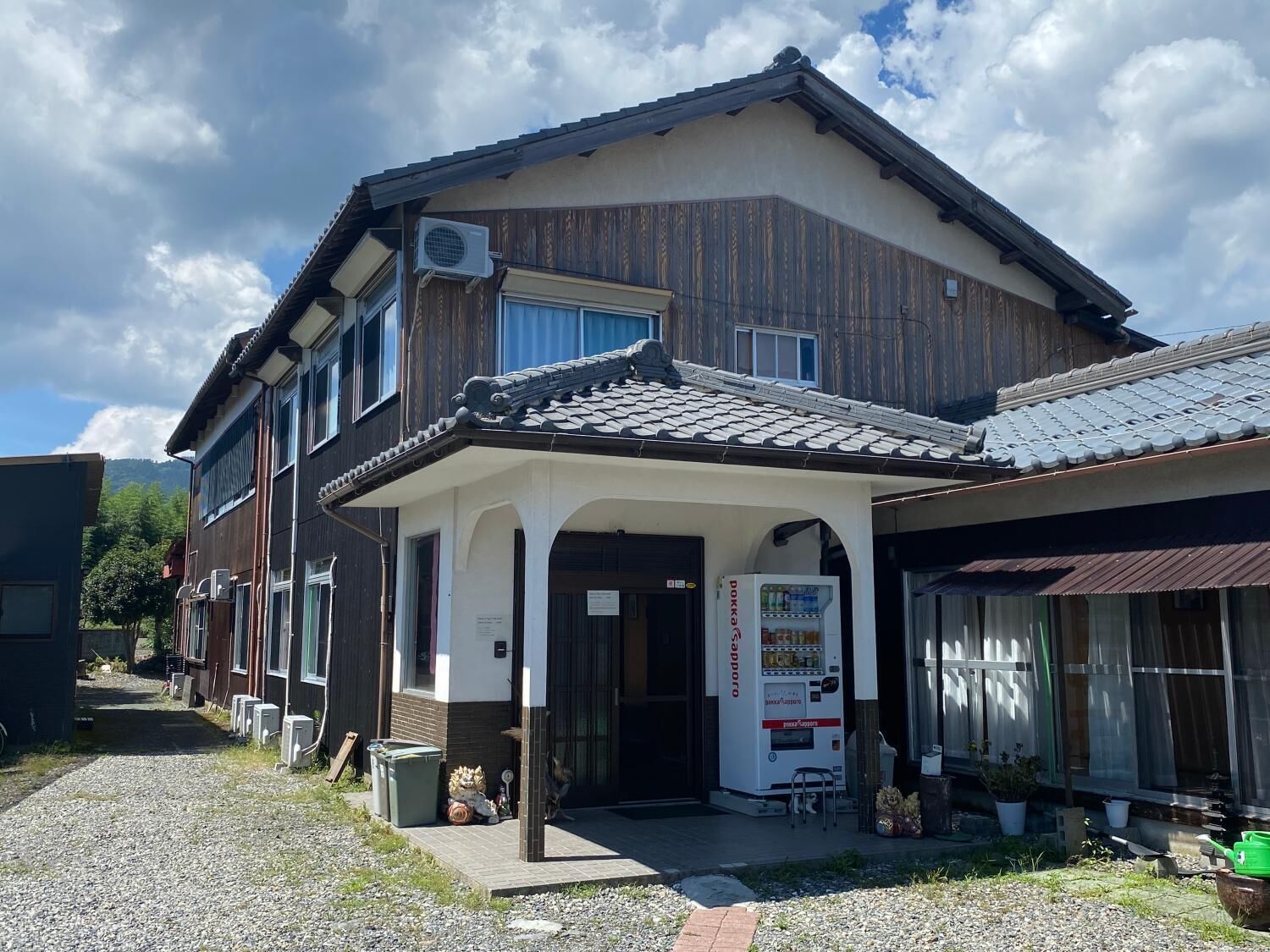 Um edifício de dois andares com telhado de telhas tradicionais e entrada coberta.