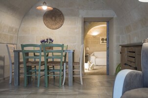 Uma área de refeições com mesa e cadeiras, luminária pendente e porta que dá para outro cômodo.