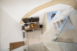 Cozinha moderna com mesa de madeira, forno embutido e guarda-corpo de vidro com vista para uma varanda.