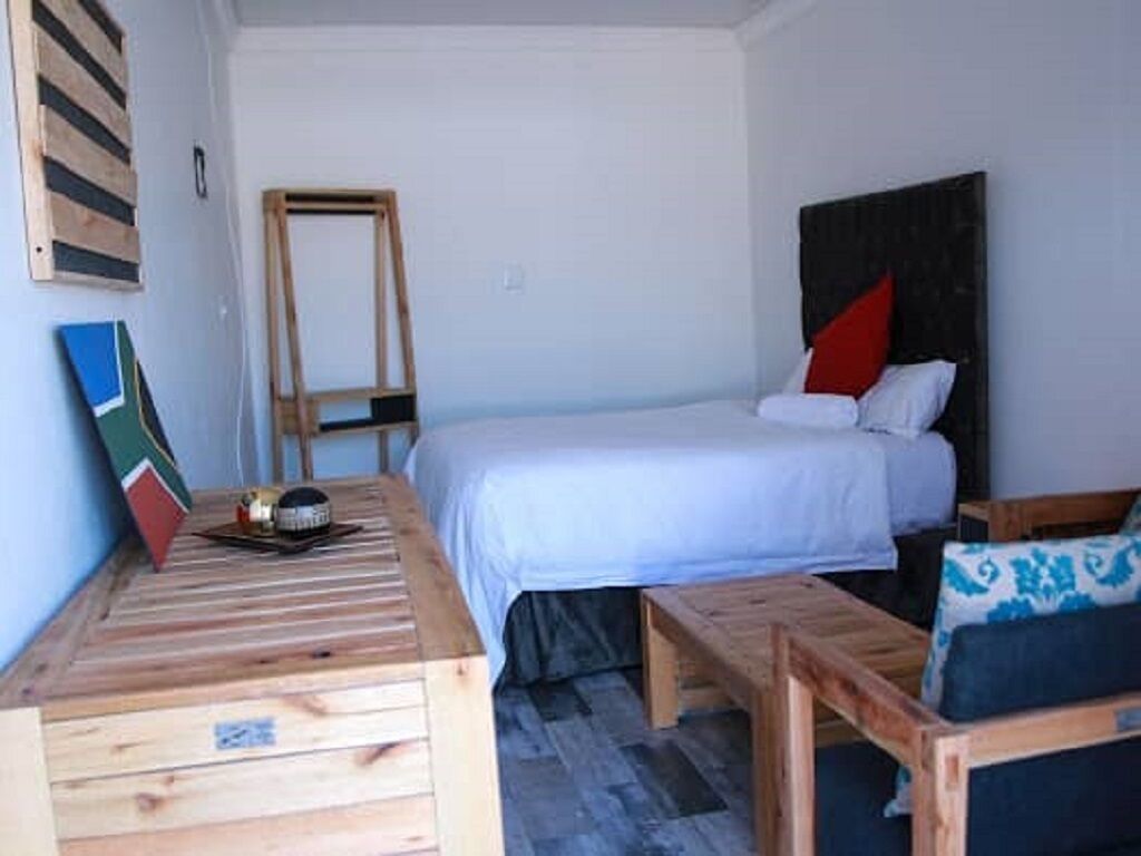 Um quarto com uma cama, uma escrivaninha de madeira, uma cadeira e um espelho.