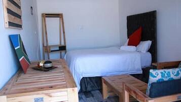 Um quarto com uma cama, uma escrivaninha de madeira, uma cadeira e um espelho.