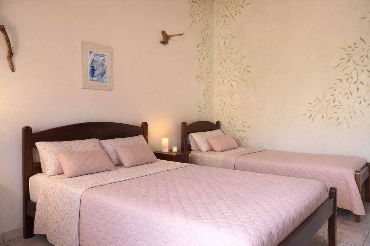 Quarto com duas camas, um quadro fixado na parede e um desenho decorativo na parede.