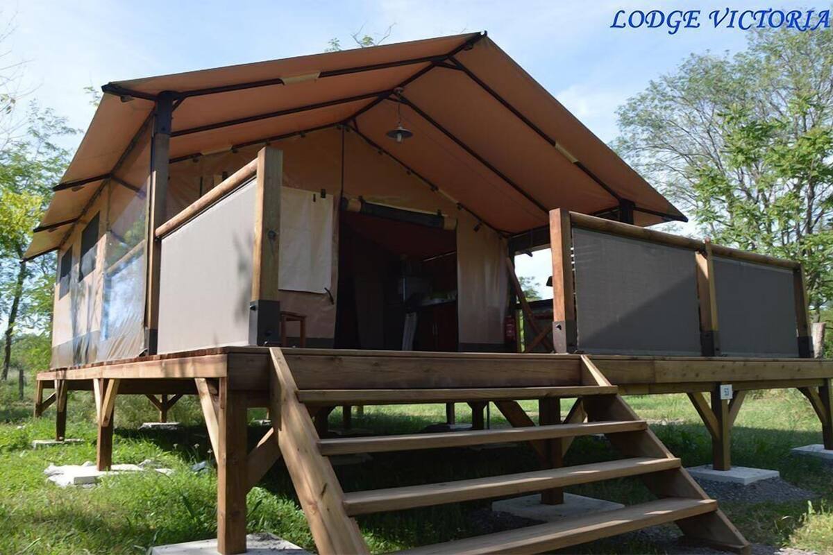 Uma cabana de madeira com telhado inclinado, varanda coberta e escada que leva à entrada.