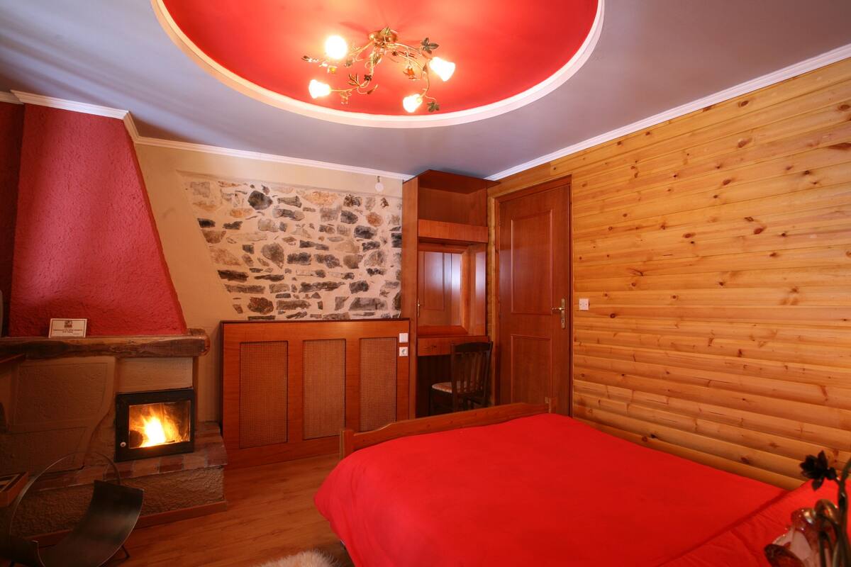 Um quarto aconchegante com lareira, cama, parede de madeira e parede de pedra.