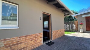 Um edifício com placa de número 5, uma porta, uma janela e um tapete de boas-vindas.