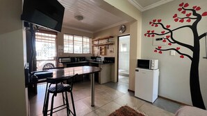 Uma cozinha compacta com área de refeições, micro-ondas e um relógio na parede.