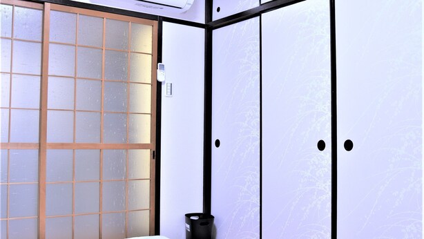 Quarto com cama, porta de correr e ar-condicionado fixado na parede.