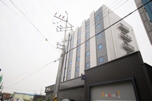 Um edifício de vários andares com placa de estacionamento, porta de garagem e infraestrutura elétrica visível.