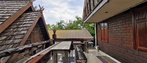 Um pátio com um banco de madeira, uma mesa de piquenique e um edifício com fachada de tijolos.