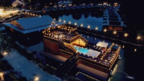 Um resort com uma grande área de piscina, vários quartos de hóspedes e um espaço externo bem iluminado.
