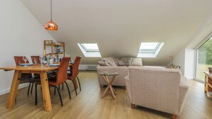 Um quarto estilo loft com área de jantar, um sofá e dois claraboias.