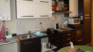 Uma cozinha compacta com armários brancos, micro-ondas, torradeira e chaleira.