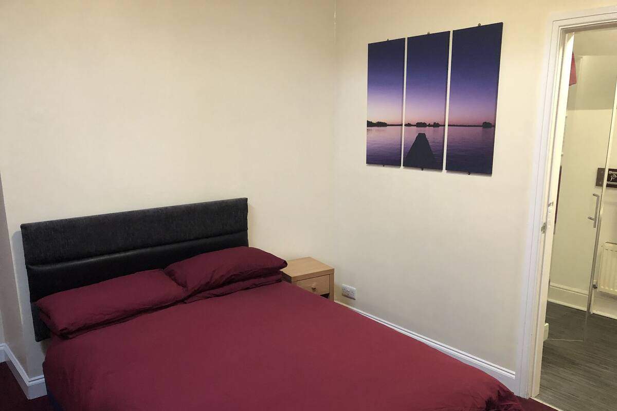 Quarto com cama, mesa de cabeceira e um quadro na parede.
