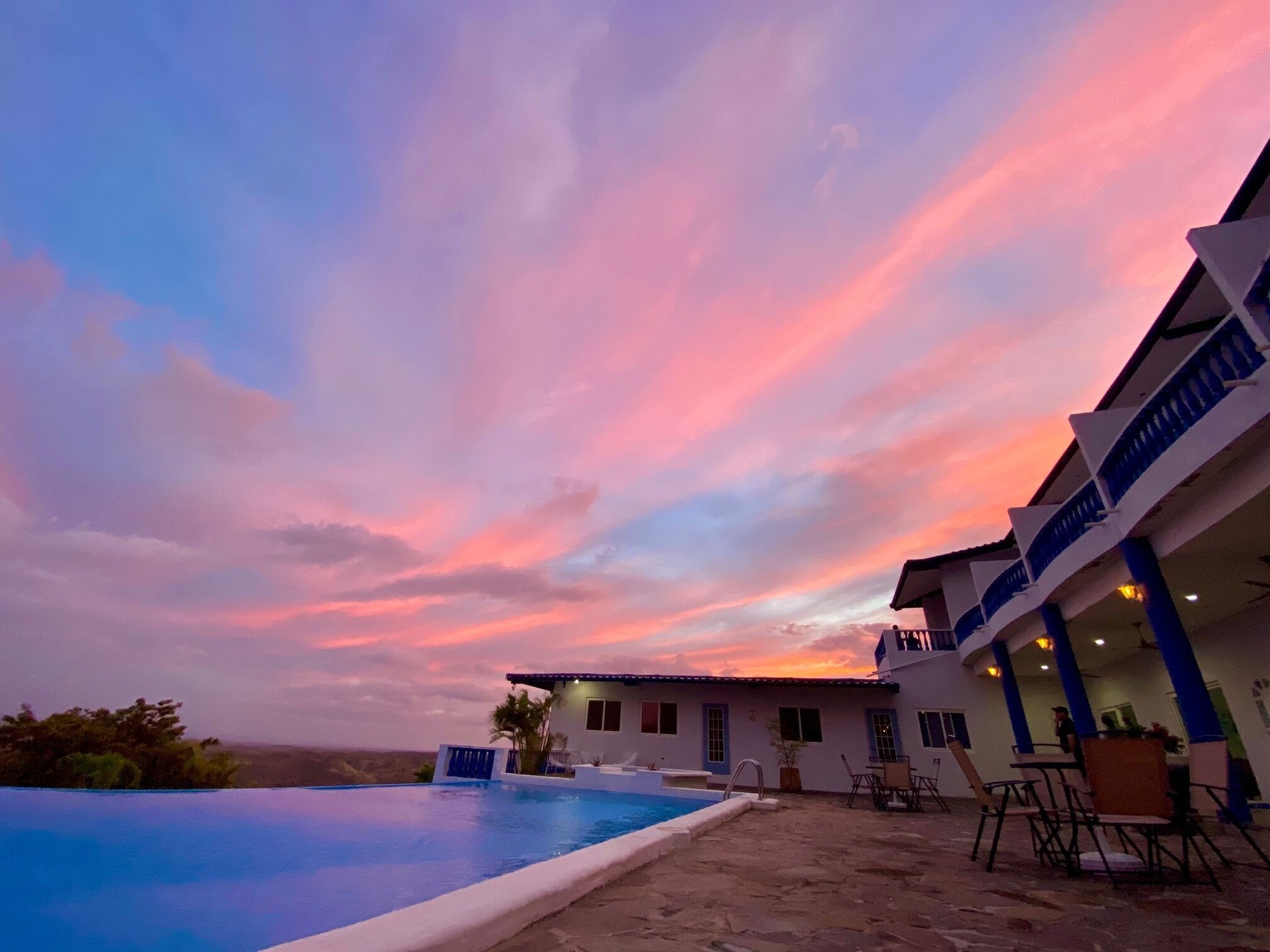Um hotel com piscina, área de estar externa e vista para o pôr do sol.