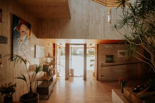 Um espaço amplo com piso de madeira, área de recepção e vista para o exterior.