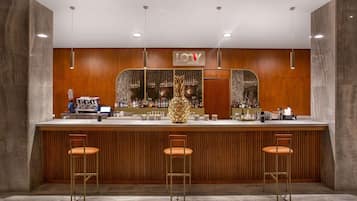 Uma área de bar com balcão de madeira, três banquetas e uma placa que diz 'LOBY BAR'.