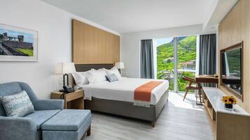 Quarto de hotel moderno com uma cama grande, uma mesa de escritório, uma cadeira e uma televisão.