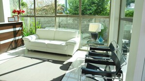 Uma sala de estar moderna com um sofá branco, uma mesa de centro de vidro e uma cadeira preta.