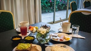 Uma mesa de café da manhã com diversos pratos, bebidas e um vaso de flores.