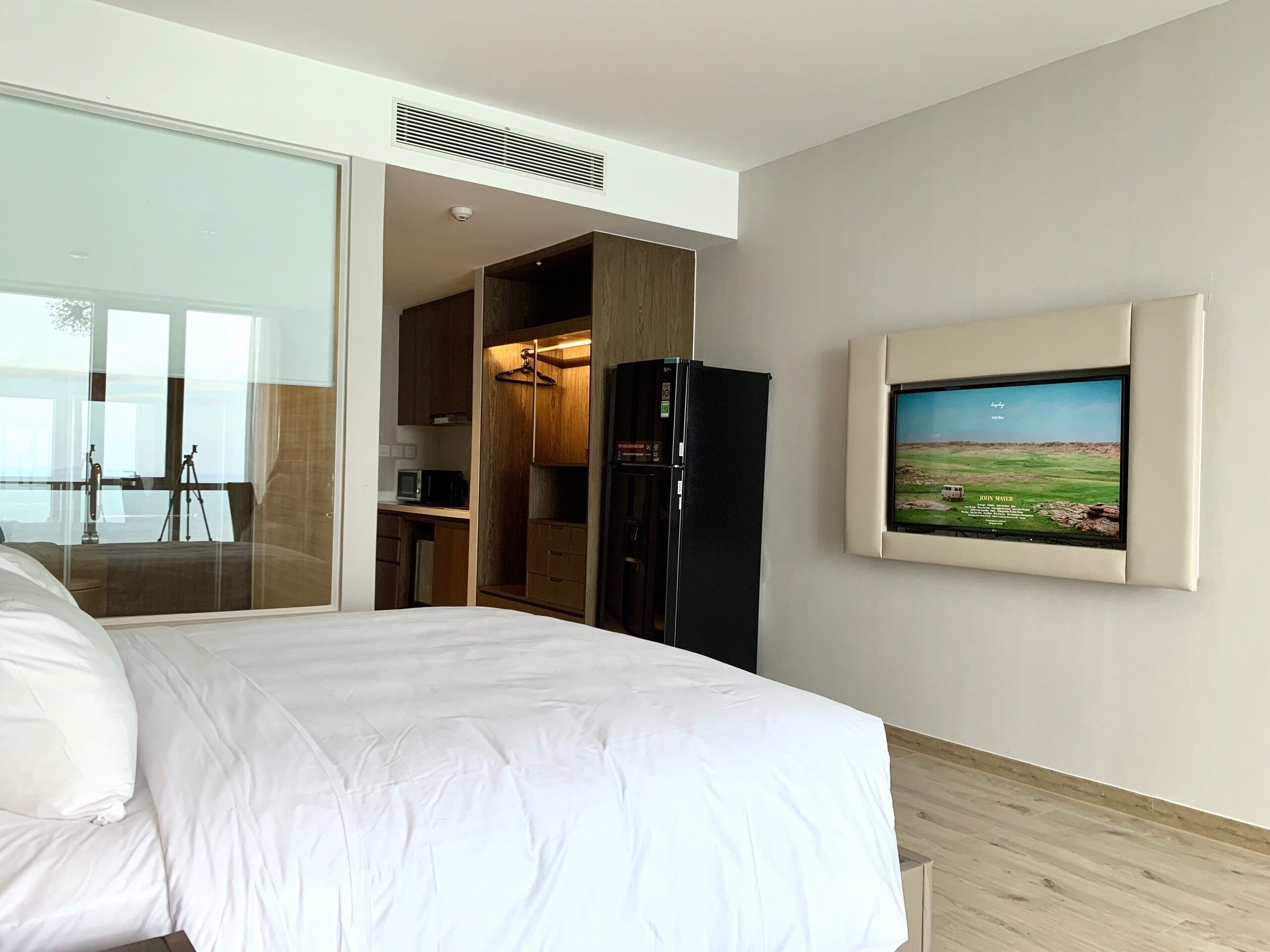 Quarto de hotel com uma cama, televisão na parede, micro-ondas e frigorífico.
