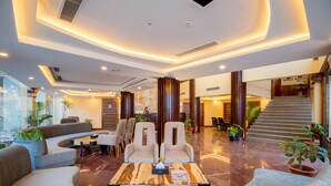 Um lobby moderno com um sofá curvo, uma mesa de centro de madeira e uma escadaria.