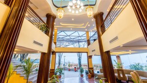 Um hall amplo com teto alto, grandes janelas e um lustre central.