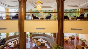 Um espaço amplo e interno com uma área de estar curvo, uma varanda com assentos externos e um teto com luminária decorativa.