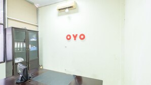 Uma mesa de recepção com uma placa com o nome "OYO" e uma estante de arquivos à esquerda.