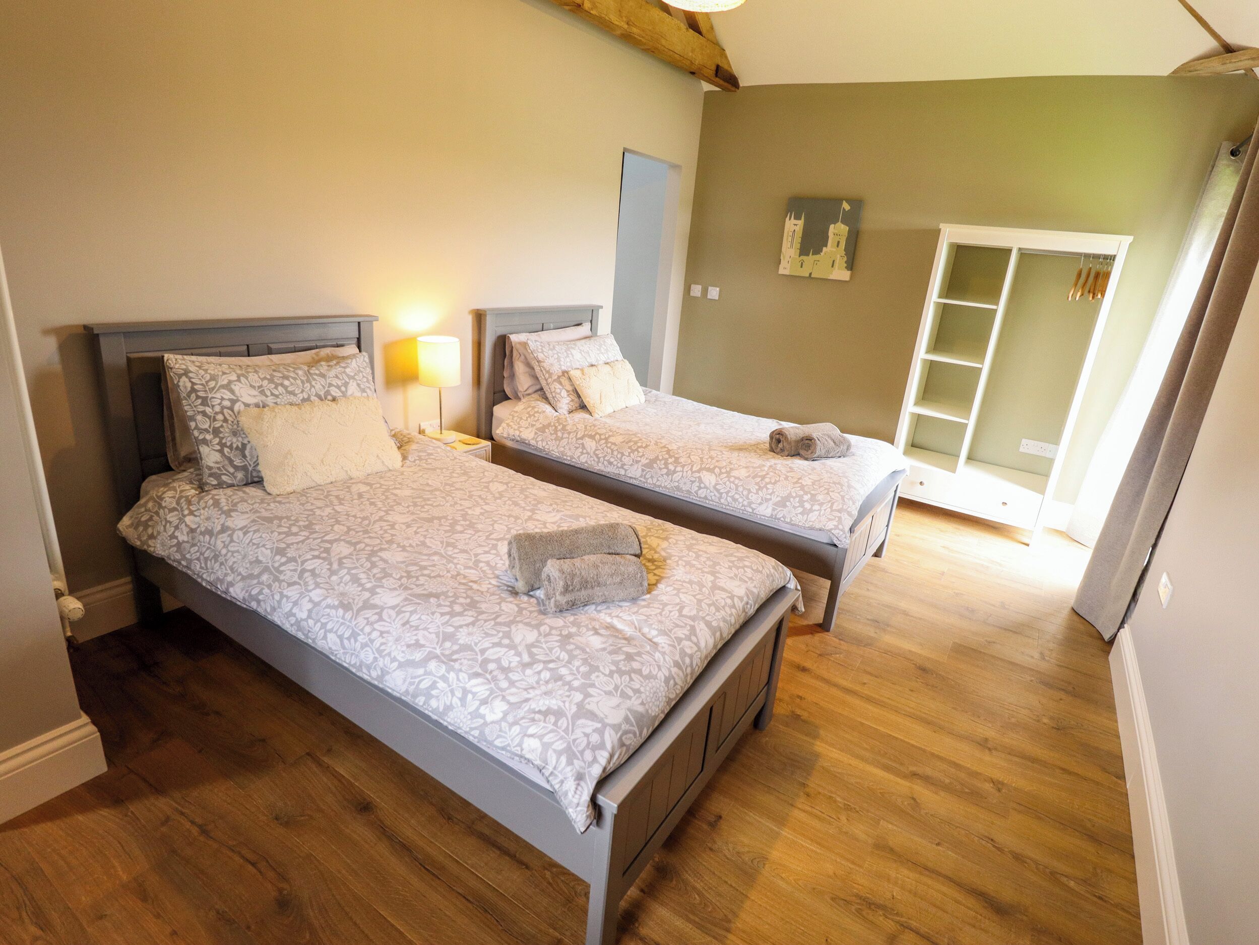 Duas camas de solteiro com roupa de cama floral, piso de madeira e vista para uma varanda.