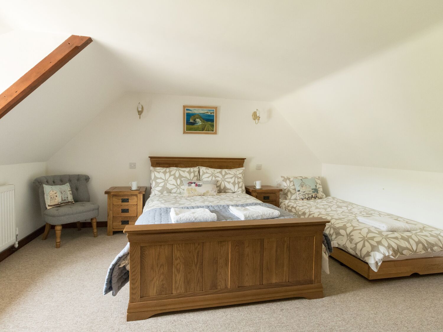 Um quarto com cama de madeira, uma cadeira, mesa de cabeceira e um quadro na parede.