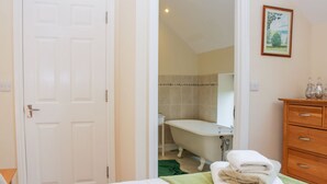 Um quarto com uma cama, um cobertor verde e uma pilha de toalhas.