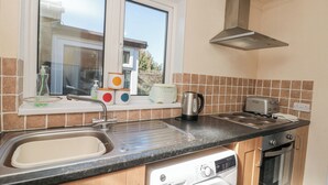 Cozinha com pia, máquina de lavar, torradeira e janela com vista para o exterior.