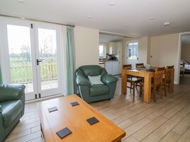 Uma sala de estar aconchegante com um sofá verde, uma mesa de jantar de madeira com quatro cadeiras e uma poltrona verde.